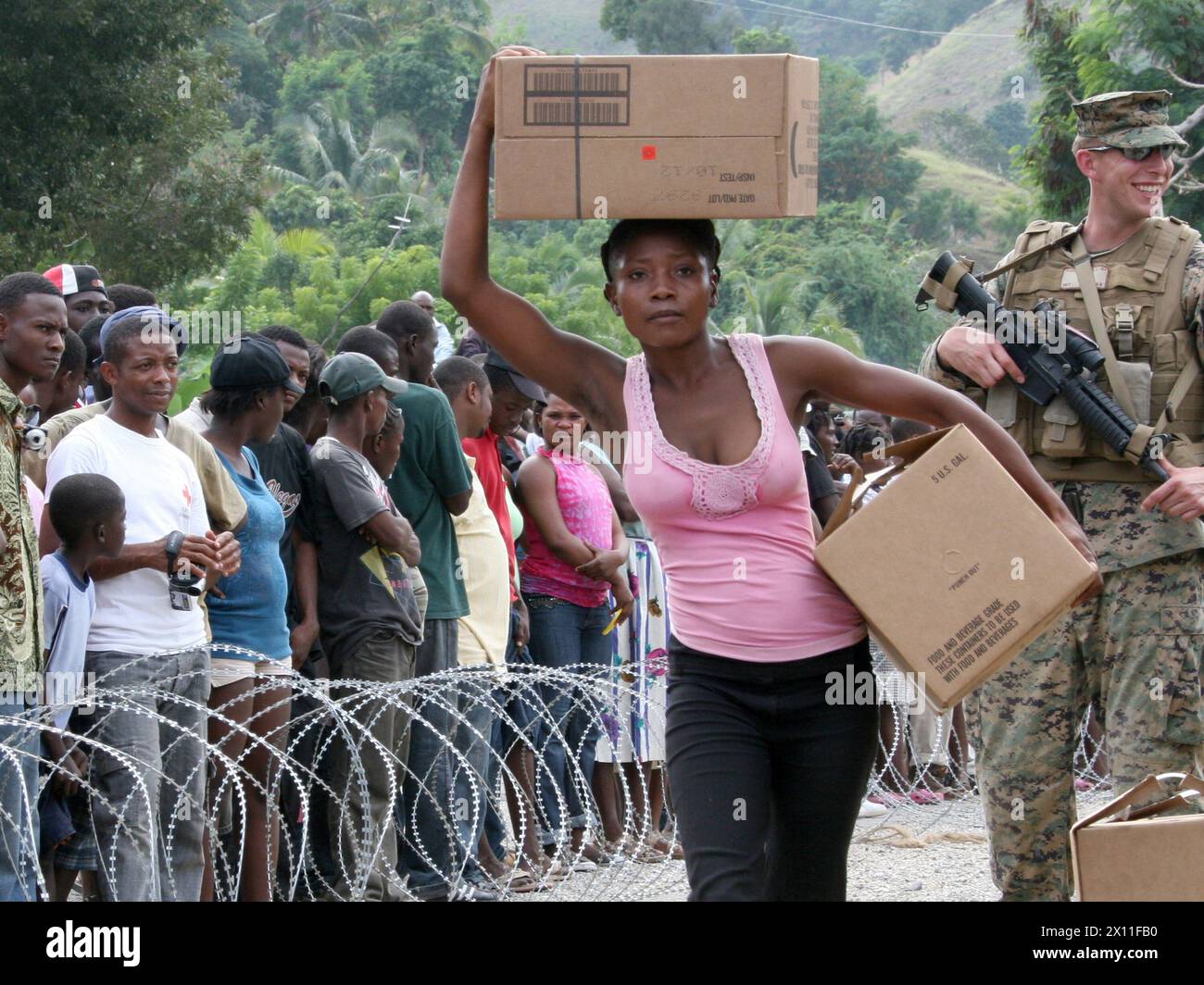 A Haitian woman carries her rations away from a distribution site set ...