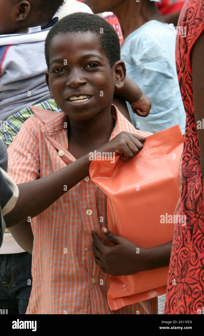 A Haitian boy holds a humanitarian rations pack at a distribution site ...