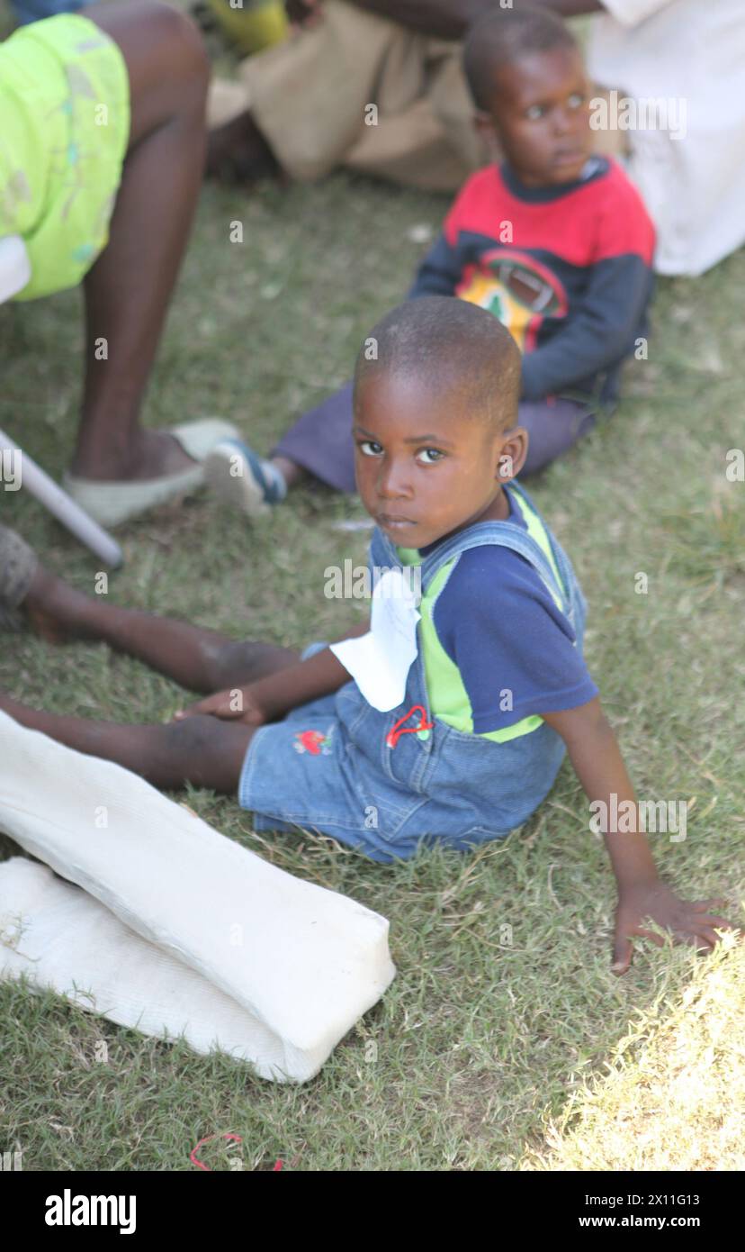 A Haitian child quietly sits outside of a Canadian medical clinic in a ...