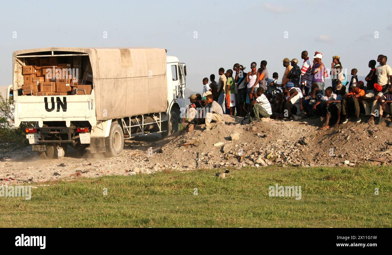 A United Nations truck loaded with food drives past a crowd of Haitians ...