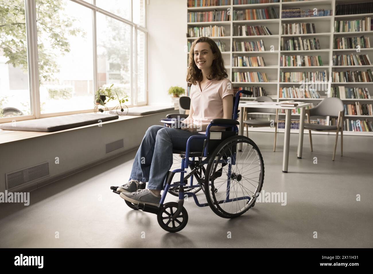 Student girl with disability sit in wheelchair in university library ...