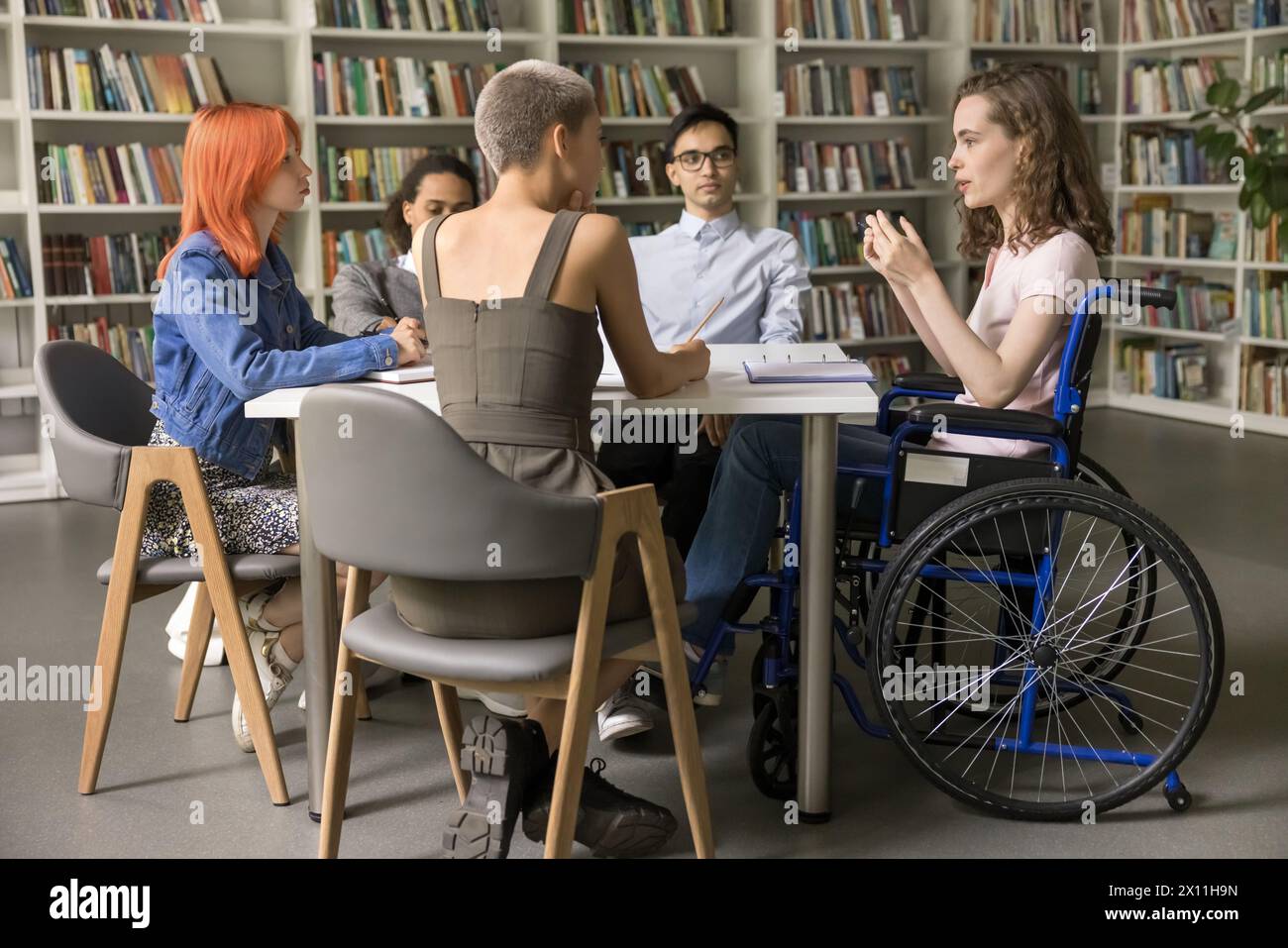 Group of diverse students listening schoolmate with physical disability ...