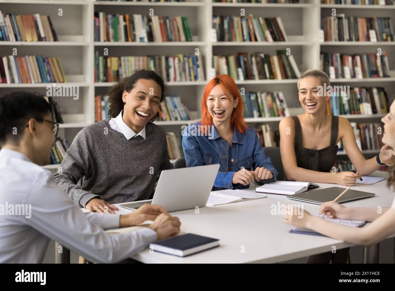 Laughing interracial group of students studying in library Stock Photo ...