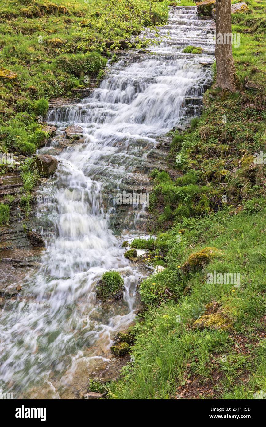 Waterfall with water flowing down a hill Stock Photo - Alamy