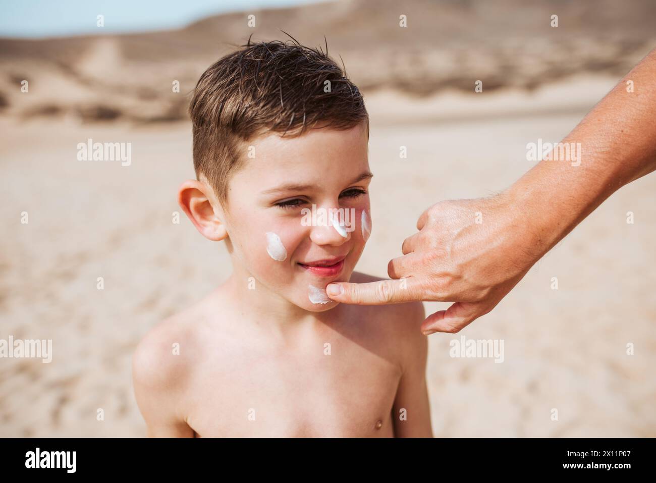 Boy with sunscreen lotion on face. Young boy si protected from sun with ...