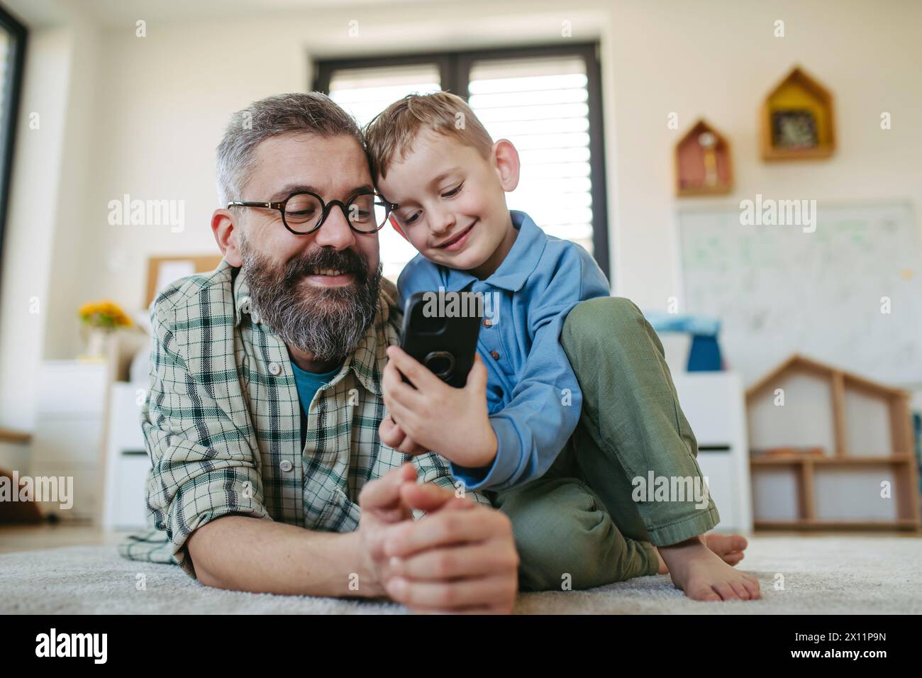 Little boy watching cartoon movie on smartphone with father, lying on ...