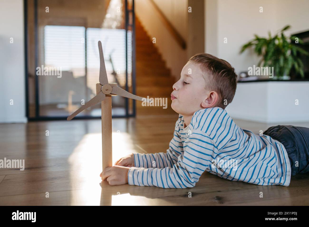 Boy blowing into blades of wind turbine model. Concpet of renewable ...