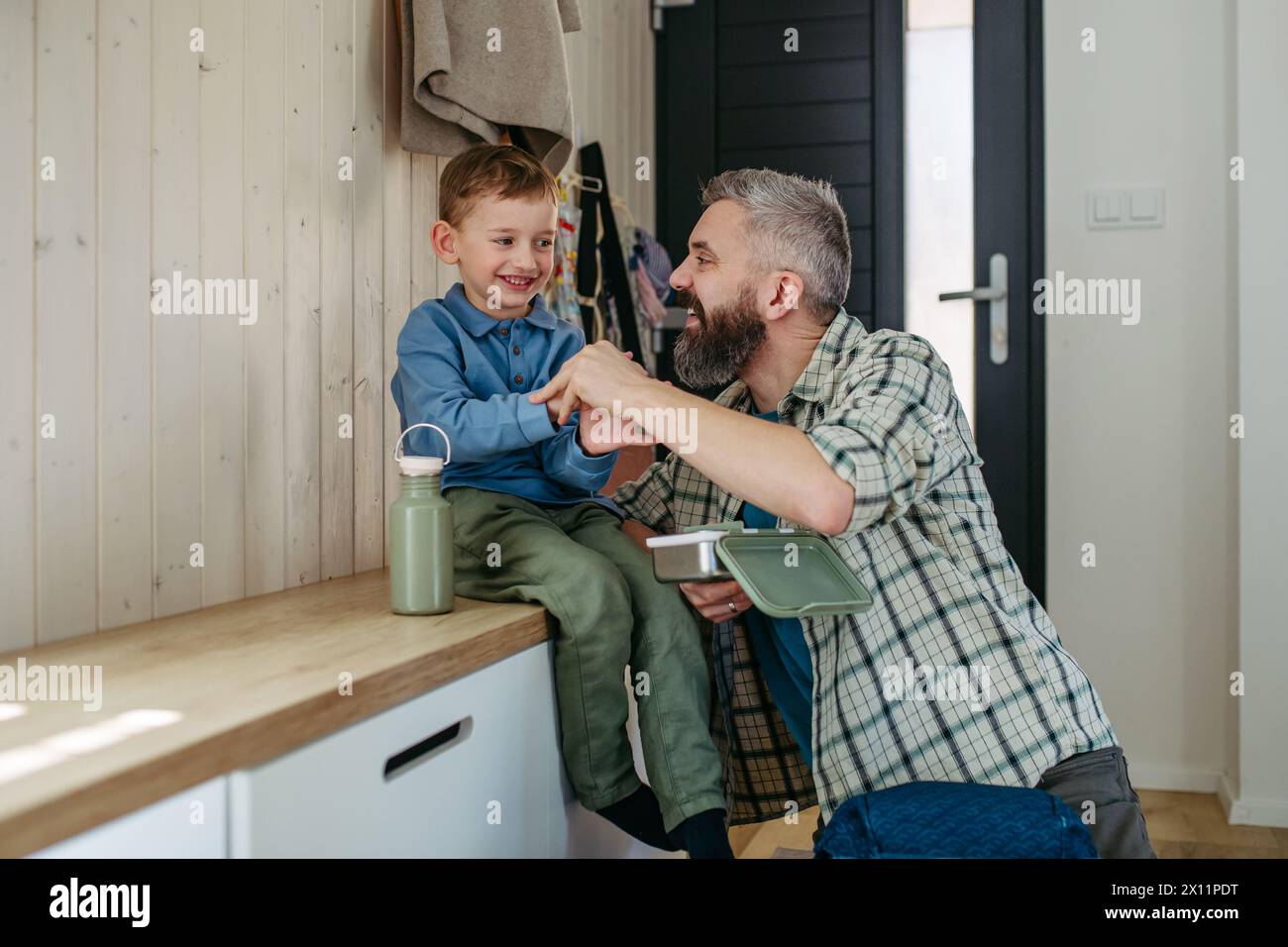 Father helping son get ready for kindergarten, preschool. Putting coat ...