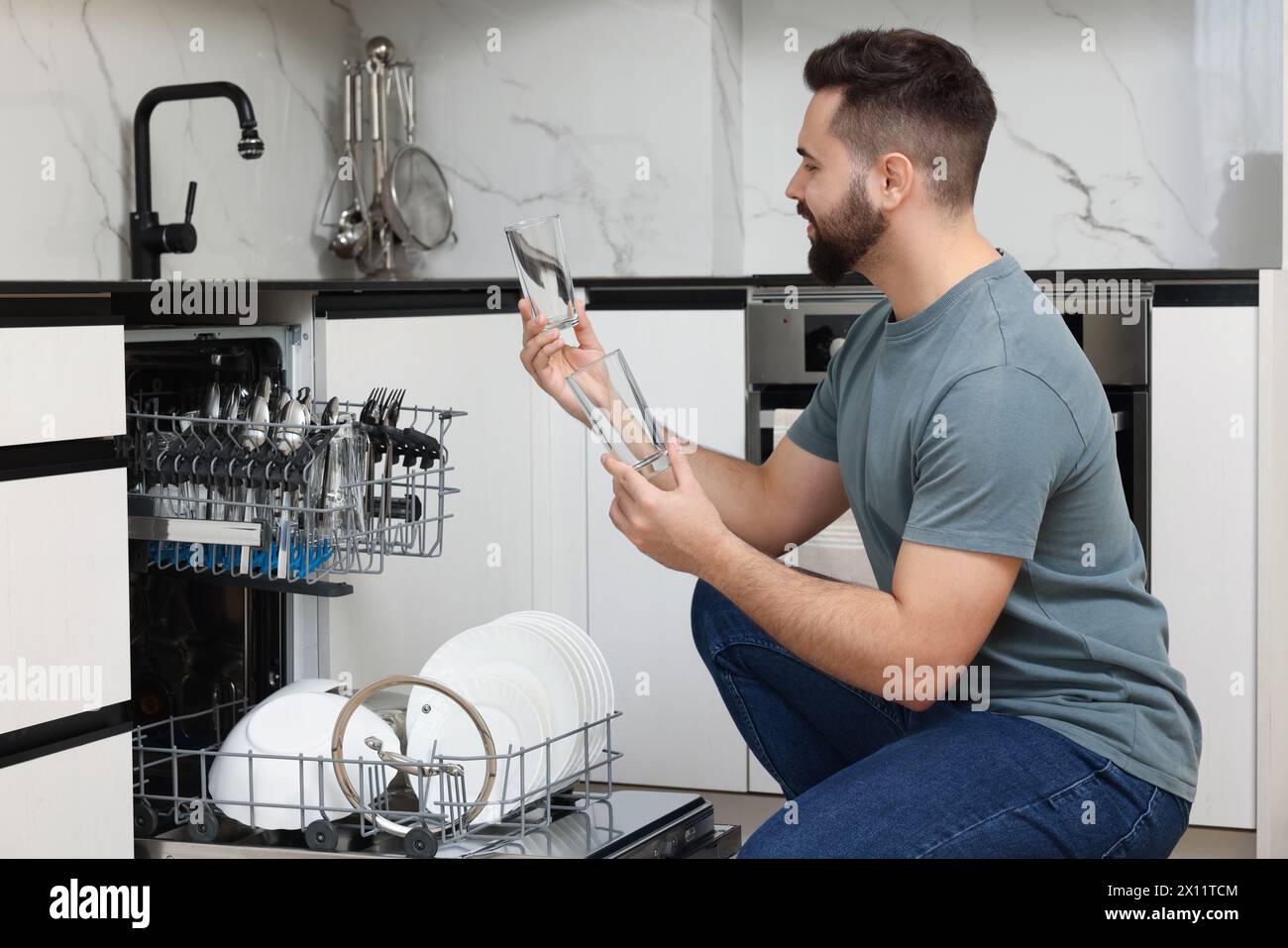 Man loading dishwasher with glasses in kitchen Stock Photo - Alamy