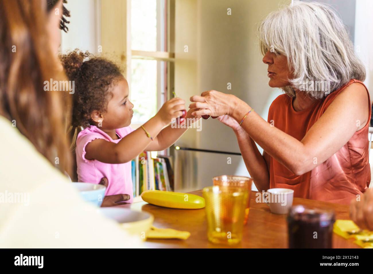 Toddler engages with their grandparent over breakfast- sharing the ...
