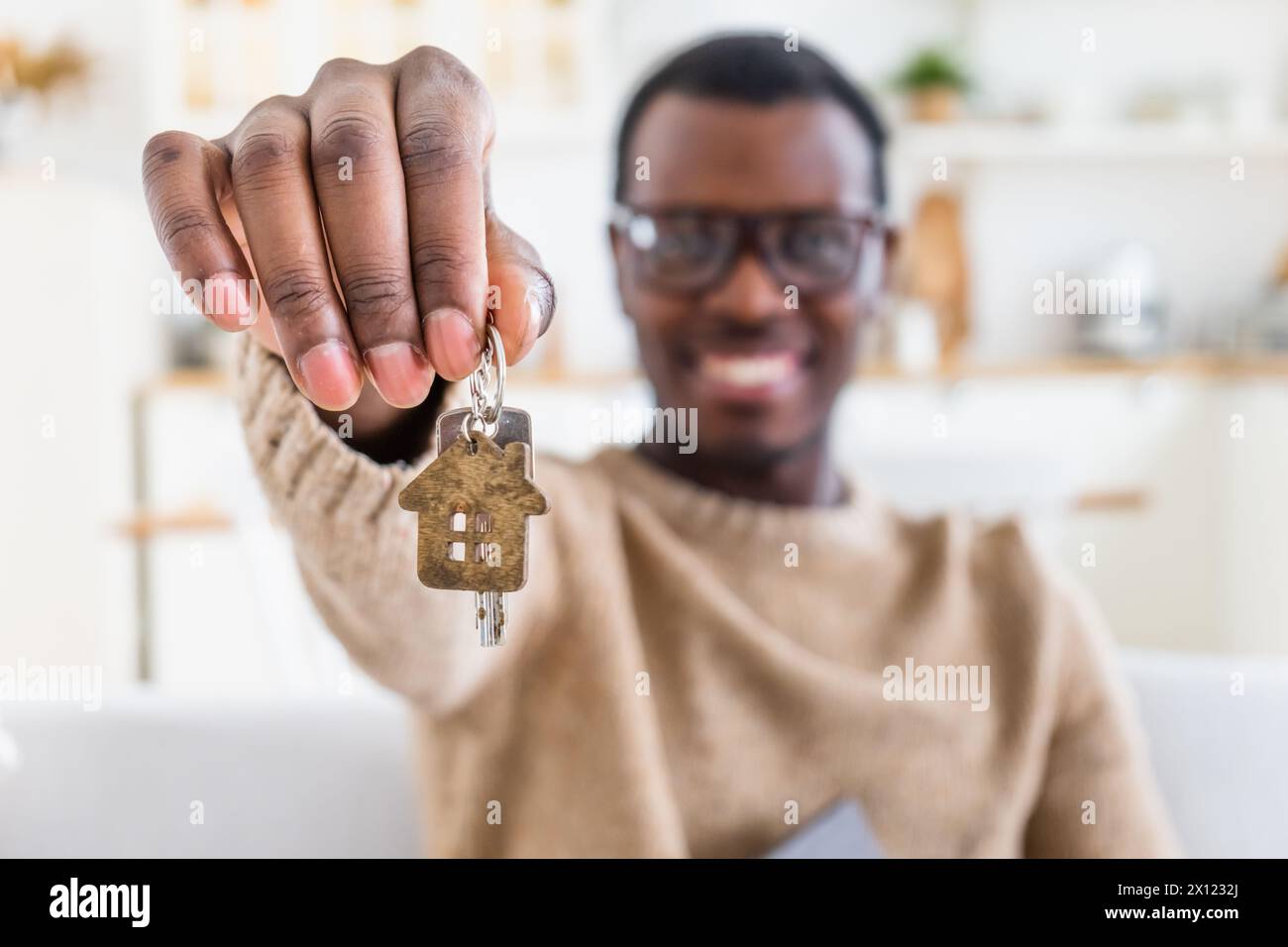 A cheerful African American man holds up a set of house keys with a ...
