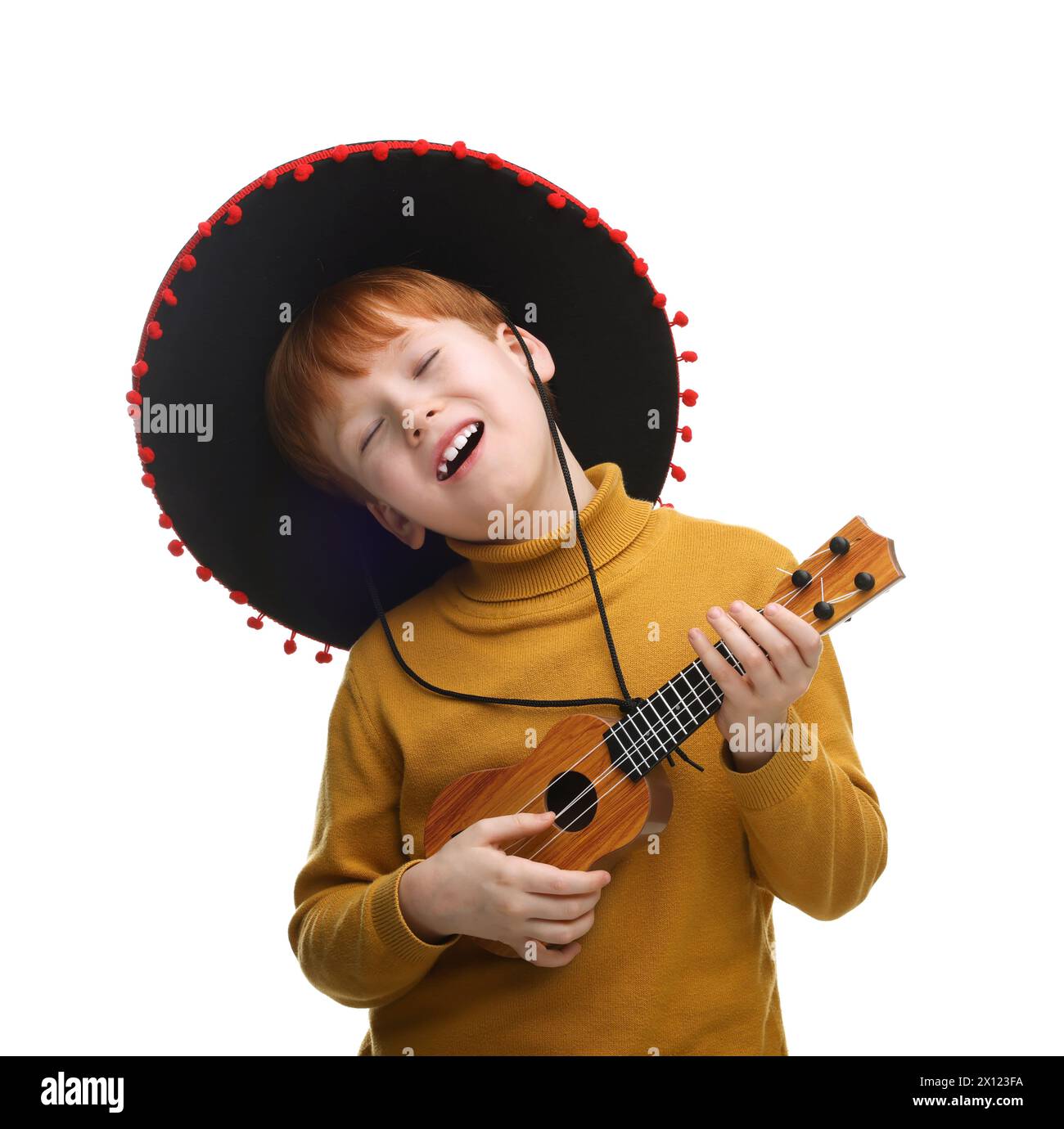 Cute boy in Mexican sombrero hat playing ukulele and singing on white ...