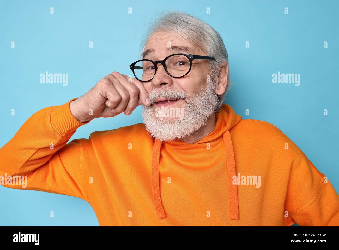 Senior man touching mustache on light blue background Stock Photo - Alamy
