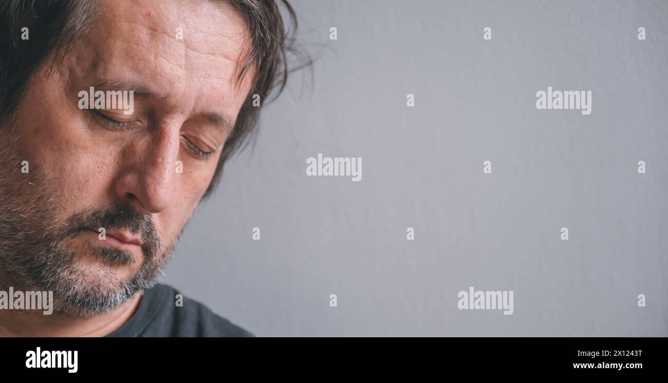 Tired sleepy man leaning his head against the wall with eyes closed ...