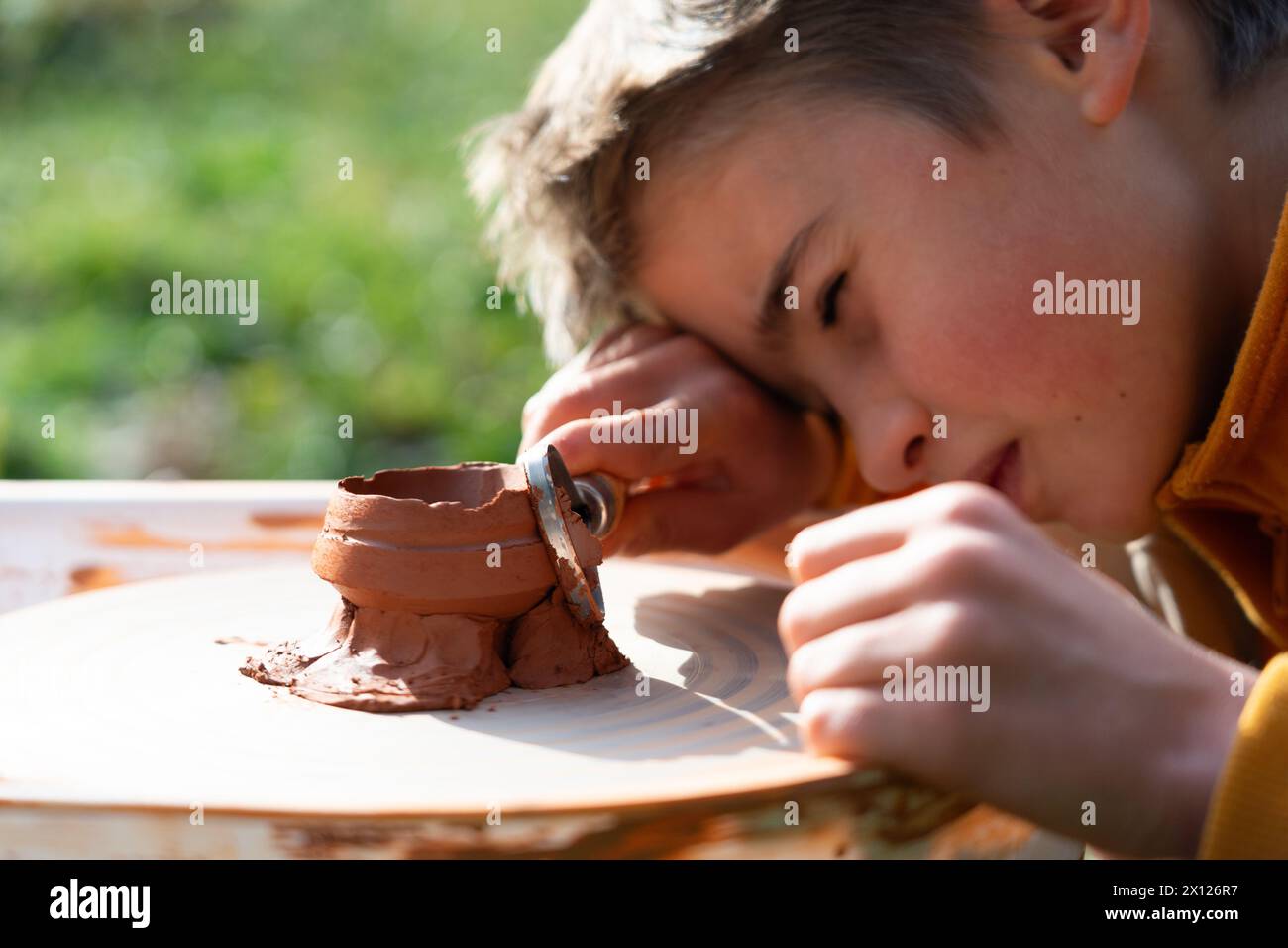 Boy trimming a piece of clay to make pottery on the potter's wheel ...