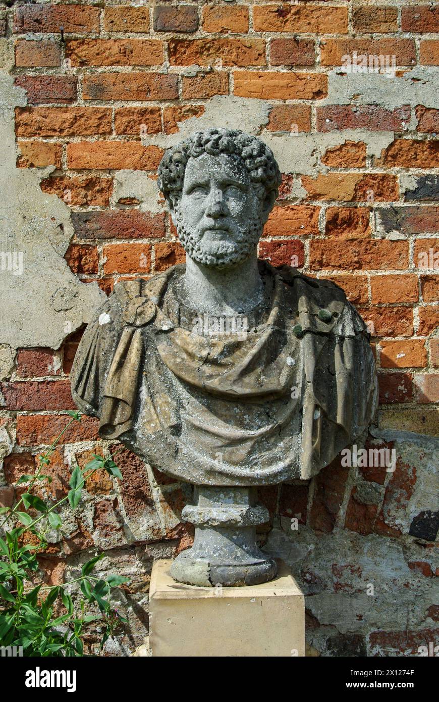 Weathered stone bust of a Roman Emperor against an old brick wall, Walled Garde, Turvey House ...