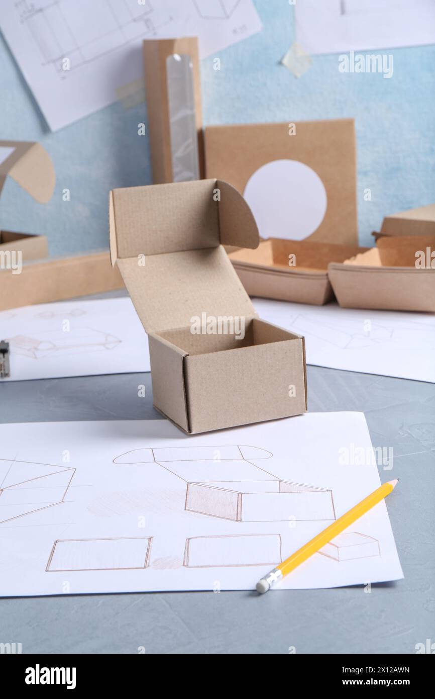 Creating packaging design. Drawings, boxes and pencil on blue textured ...