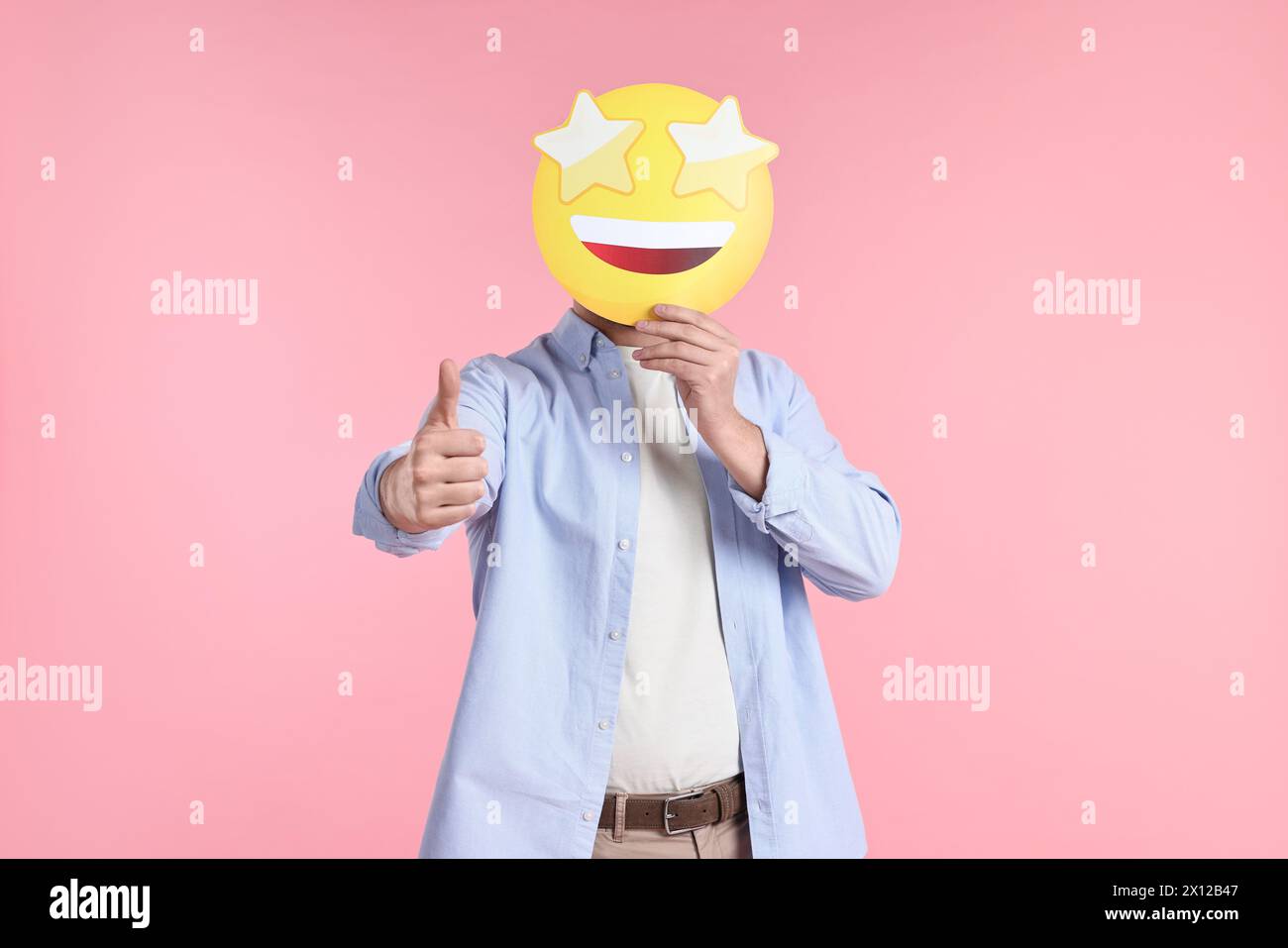 Man holding emoticon with stars instead of eyes and showing thumb up on ...
