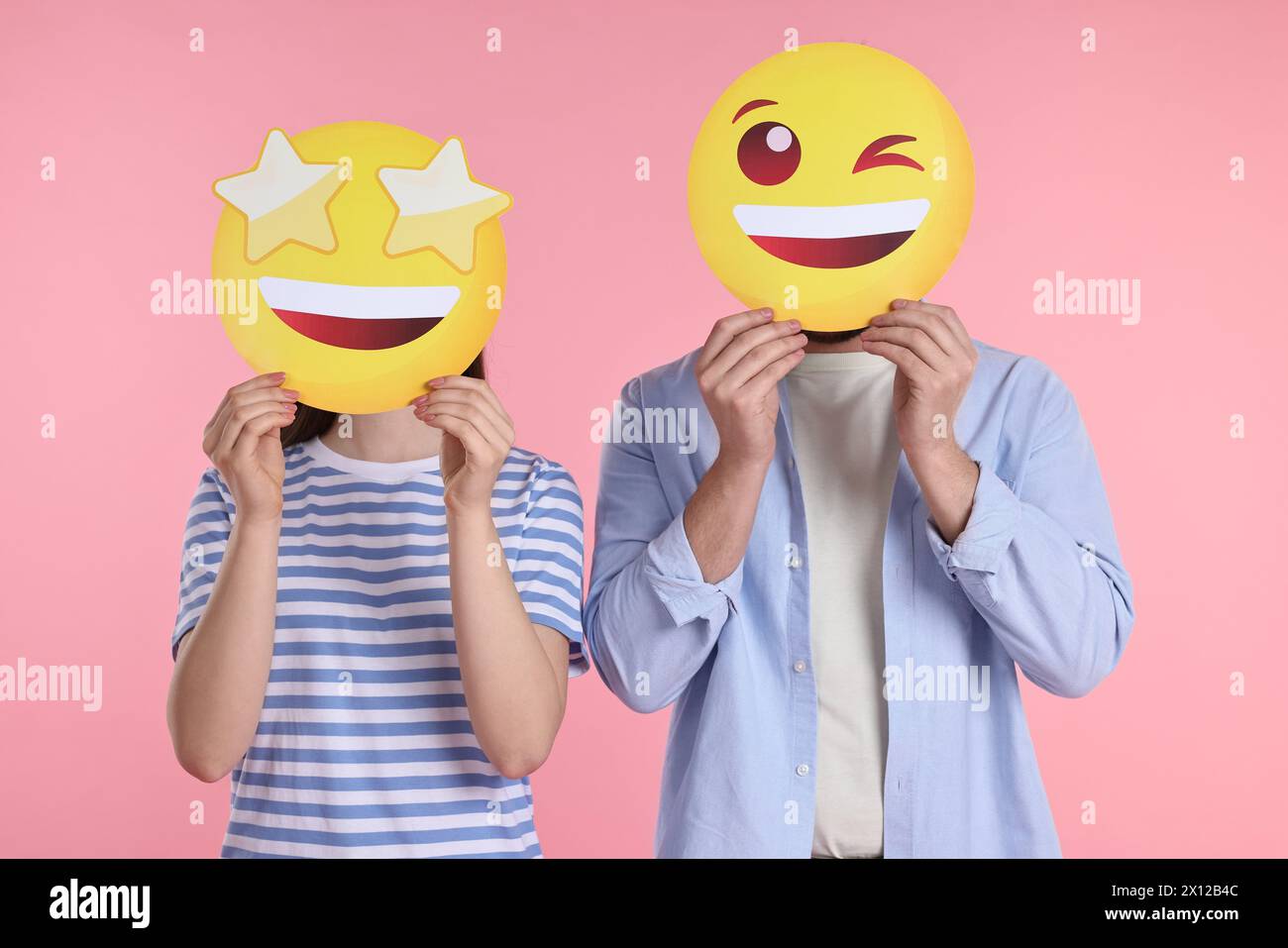 People covering faces with emoticons on pink background Stock Photo - Alamy