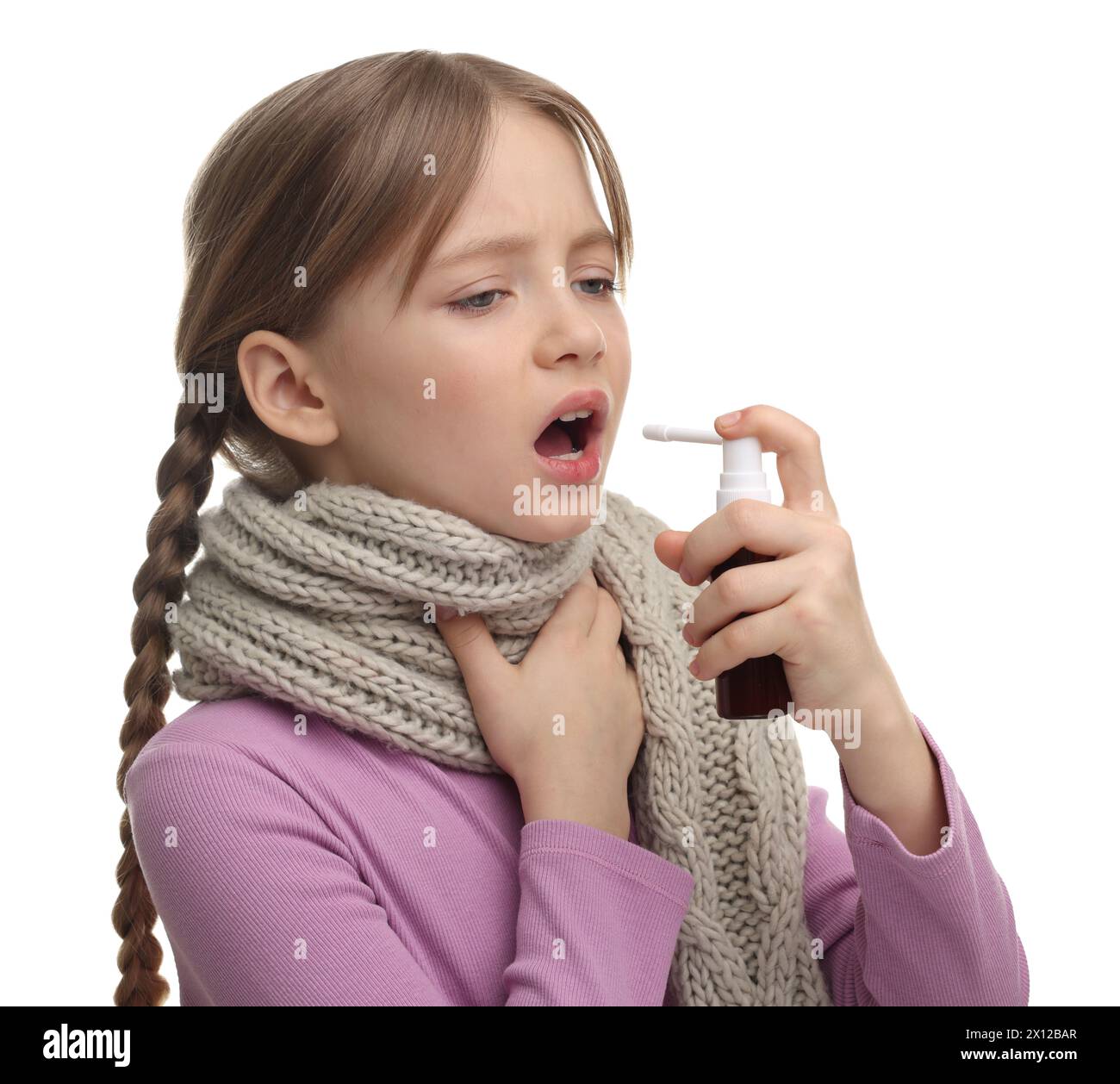 Little girl with scarf using throat spray on white background Stock ...