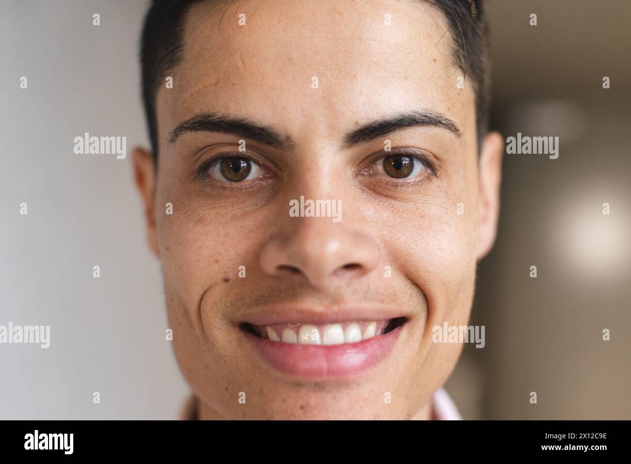 A young biracial man with short hair is smiling in a modern business ...