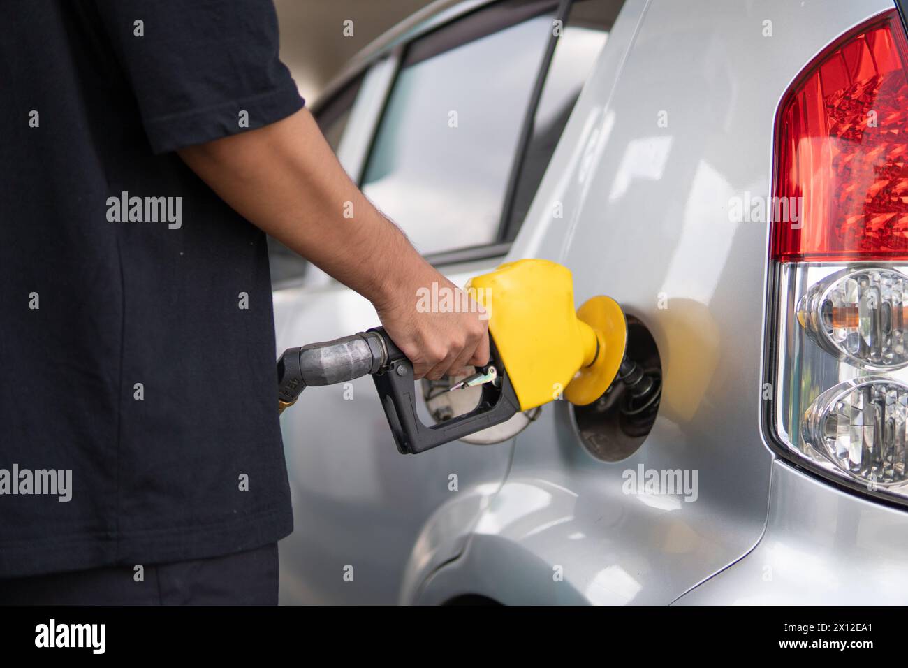 Closeup image of hand holding nozzle fuel fill oil into car tank at gas ...