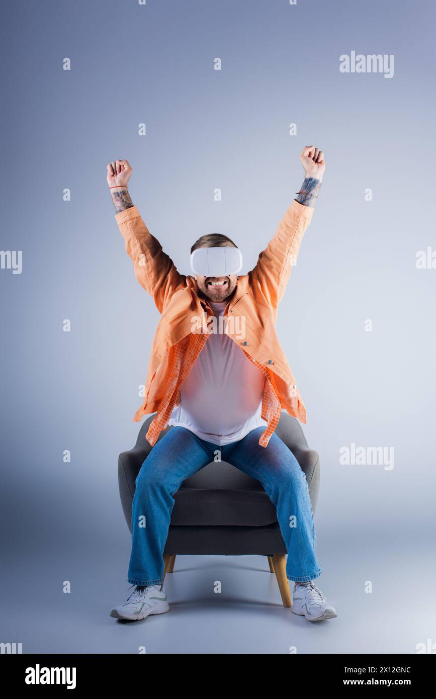 Man in VR headset sits atop chair with arms raised in celebration in a ...