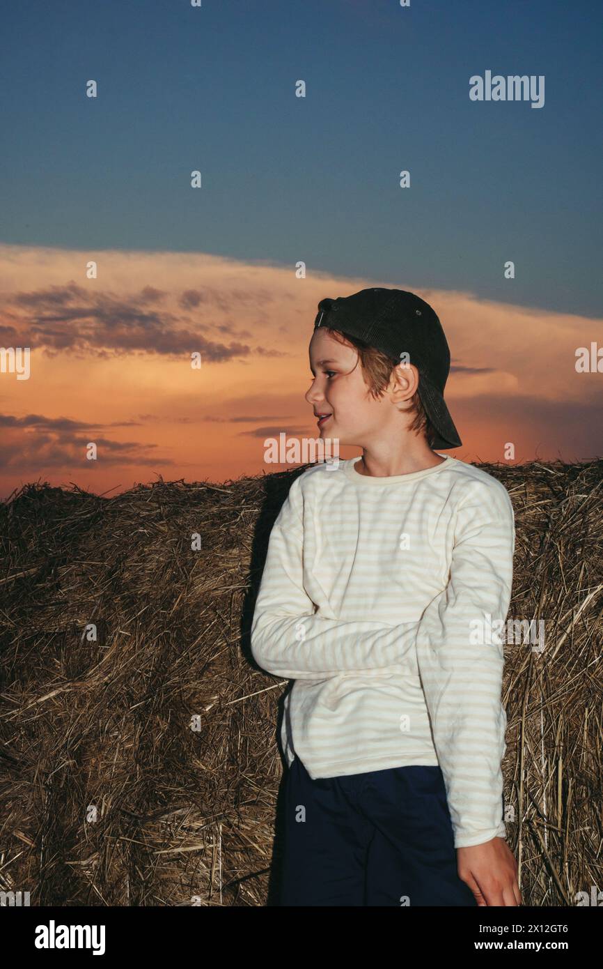 Happy child near a stack of hay field, sunset Stock Photo - Alamy