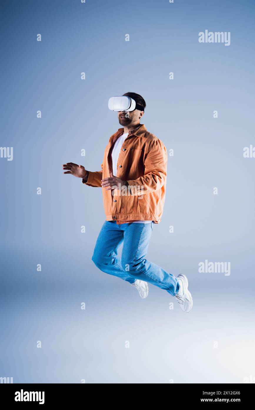 A man with a hat jumps in the air within a studio setting while wearing ...
