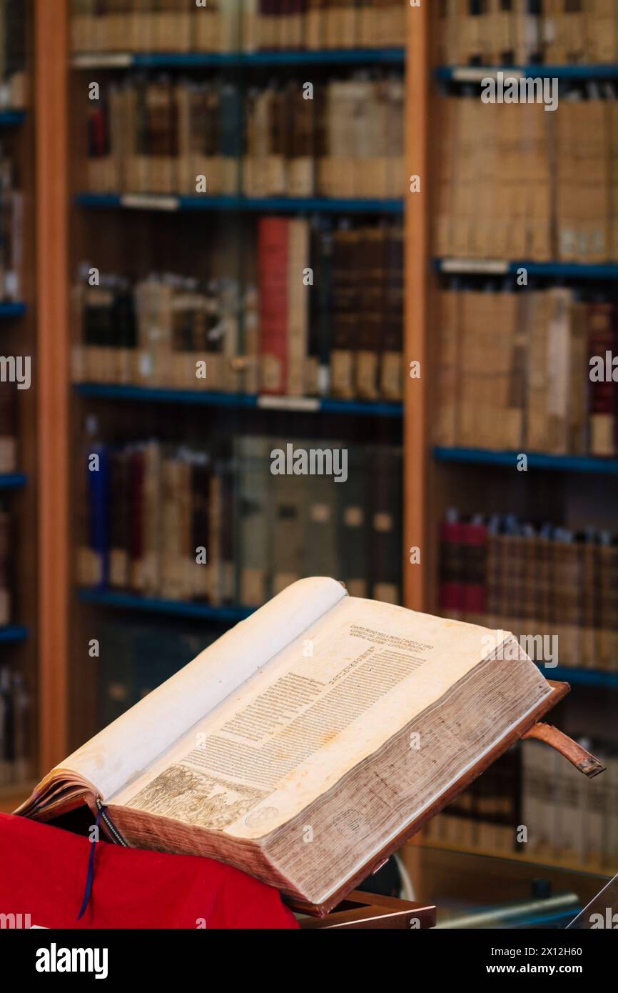 a single, old book opened in front of some bookshelves Stock Photo - Alamy