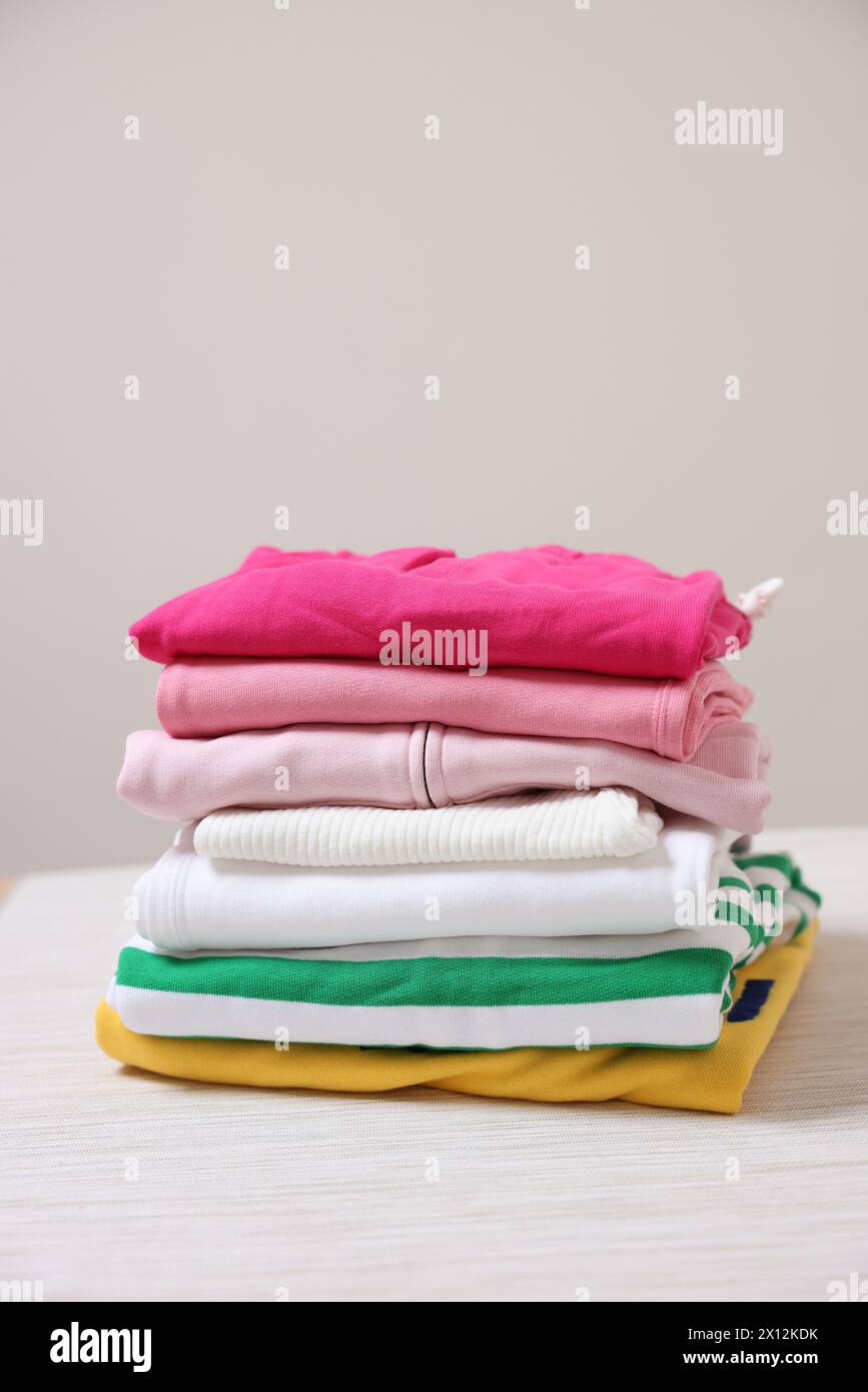 Stack of folded clothes on table against beige background Stock Photo ...