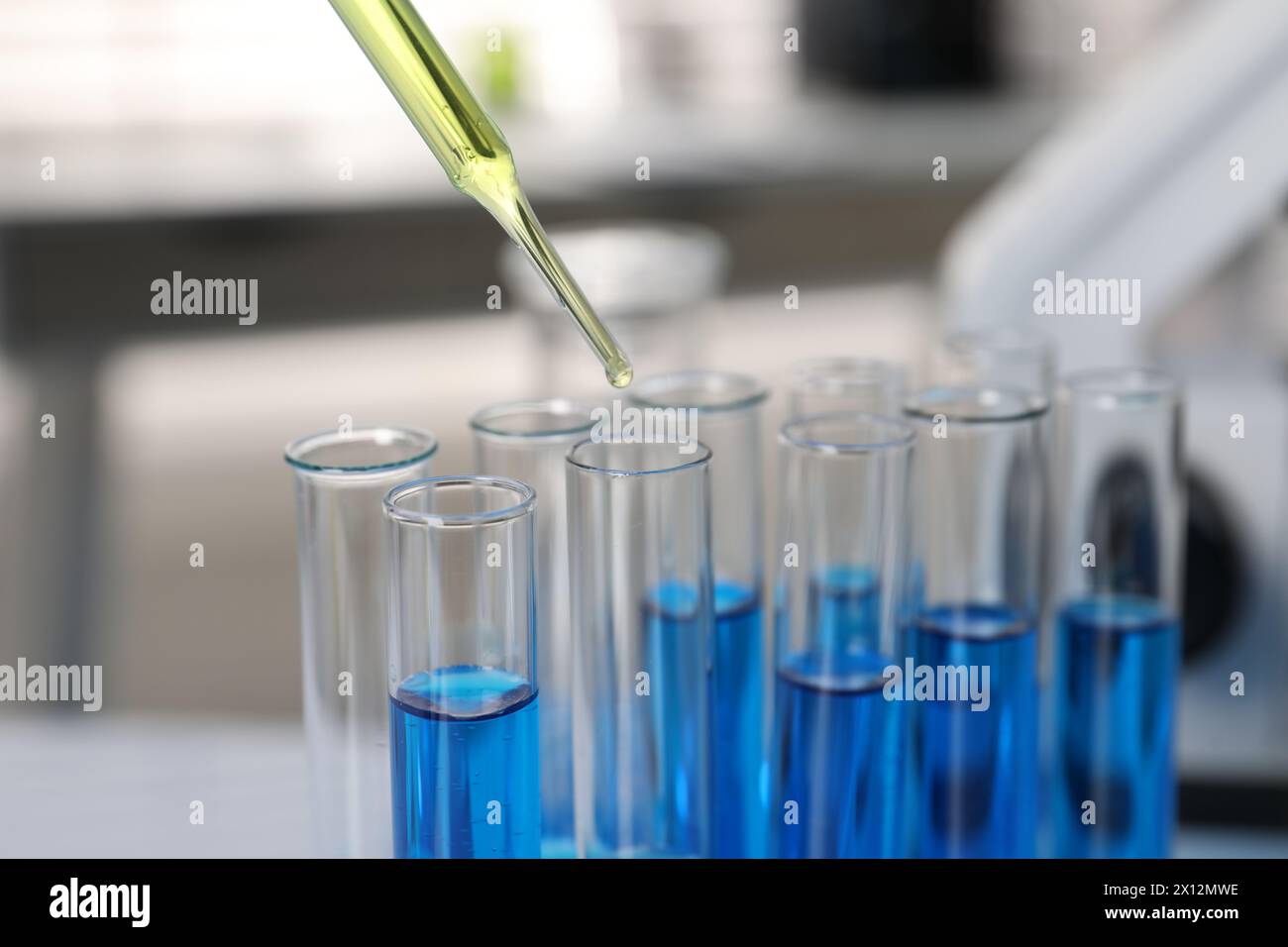 Laboratory analysis. Dripping liquid into test tubes indoors, closeup ...