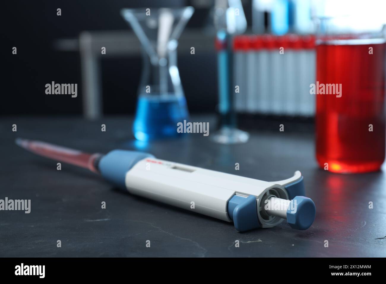 Laboratory analysis. Micropipette with liquid on black table, closeup ...