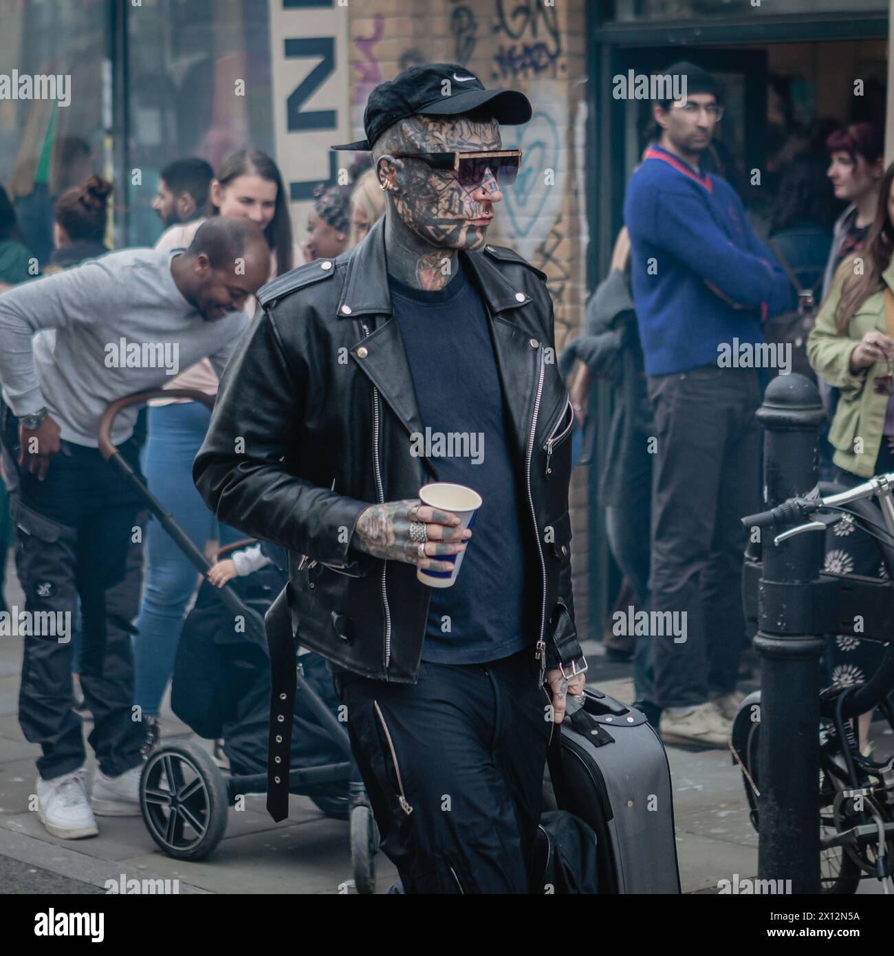 A man with facial tattoos stands out in the crowd on a busy street in ...