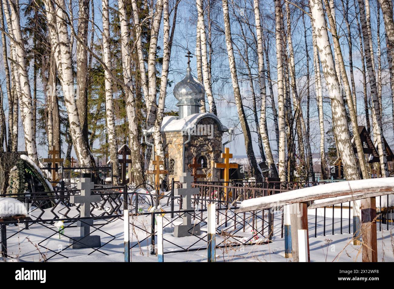 Village cemetery with Orthodox crosses and a small chapel among birches ...