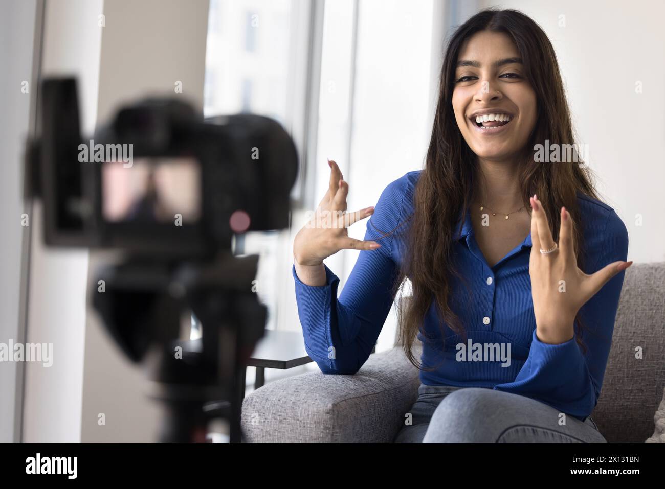 Cheerful Indian online influencer girl speaking at slr reflex camera ...