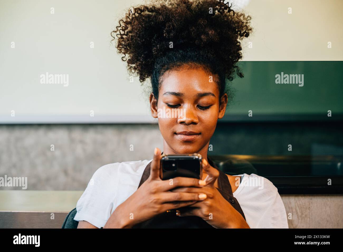 Close-up of a cheerful black barista coffee shop owner in uniform using ...