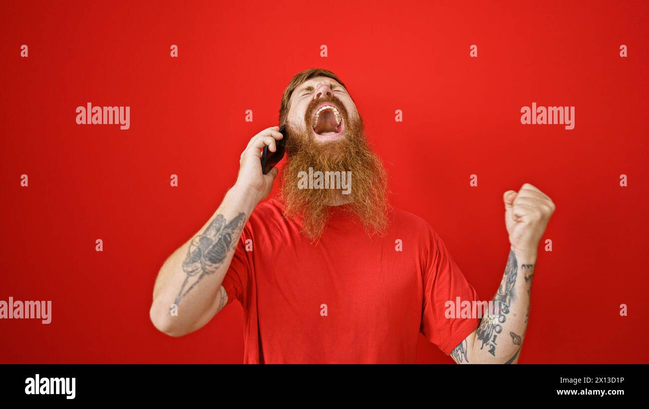 Overjoyed young redhead man ecstatically celebrating while speaking on ...