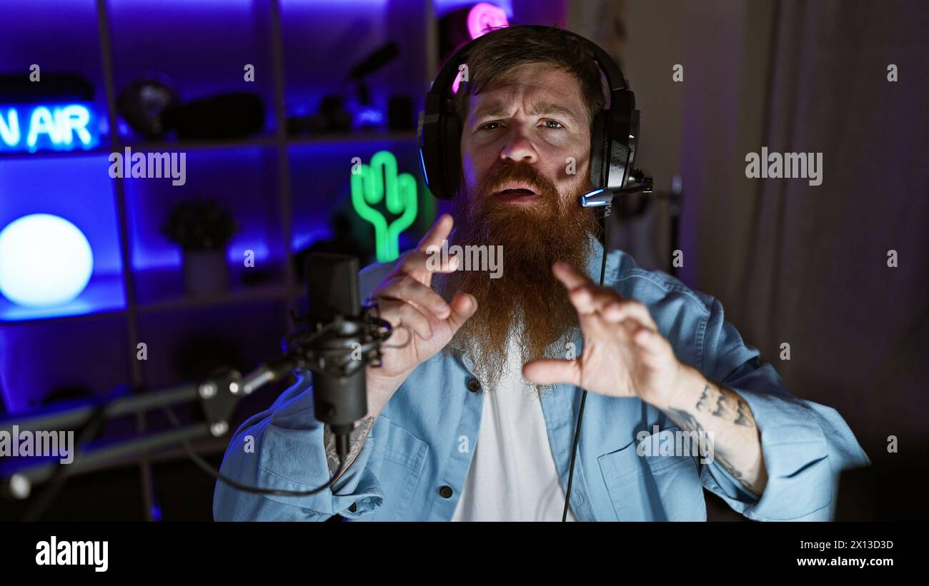 Young redhead man streamer wearing headphones speaking at gaming room ...