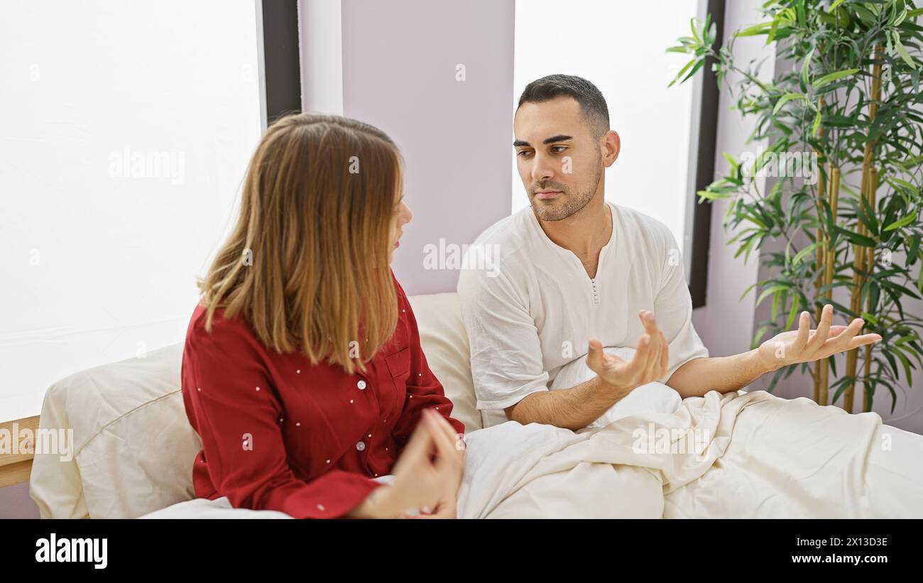 A man and woman converse earnestly in a bright bedroom setting ...