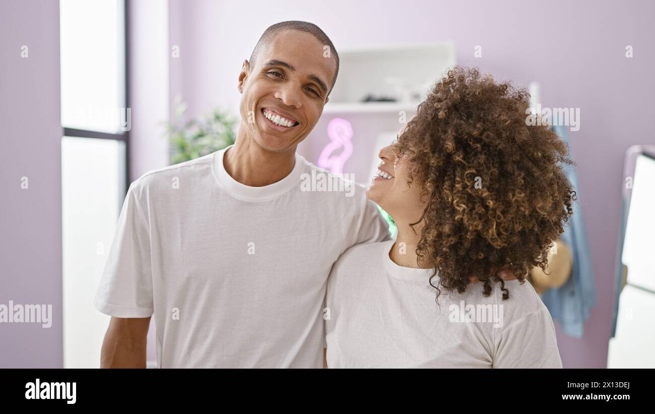 Confident, beautiful couple hugging and smiling in their cozy home ...