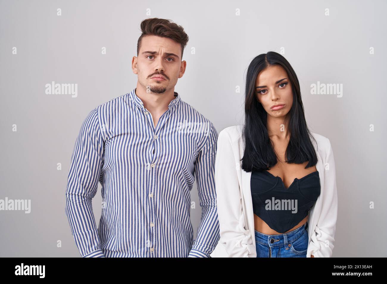 Young hispanic couple standing over white background depressed and ...