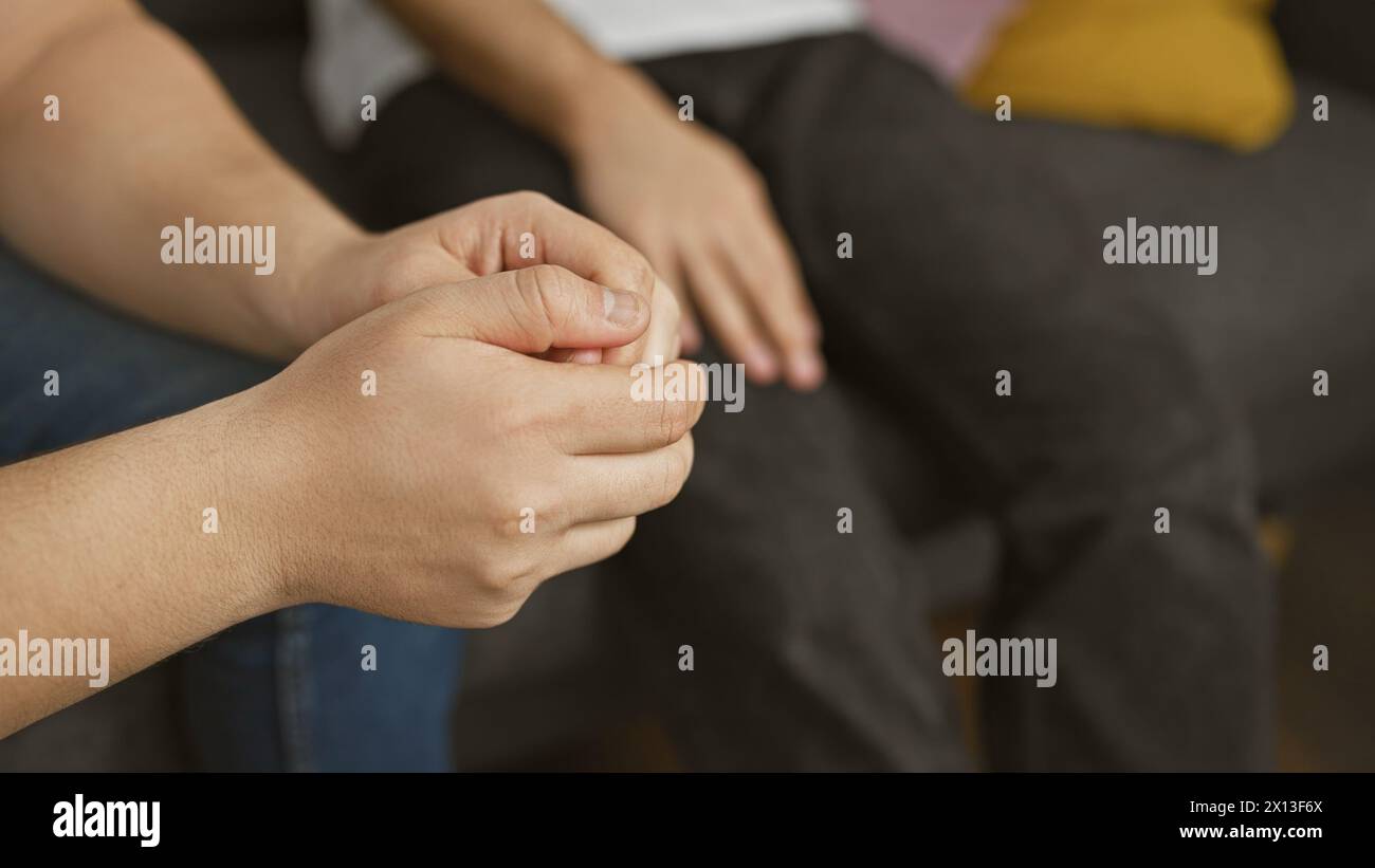 Two men hold hands in a display of comfort and support in an intimate ...