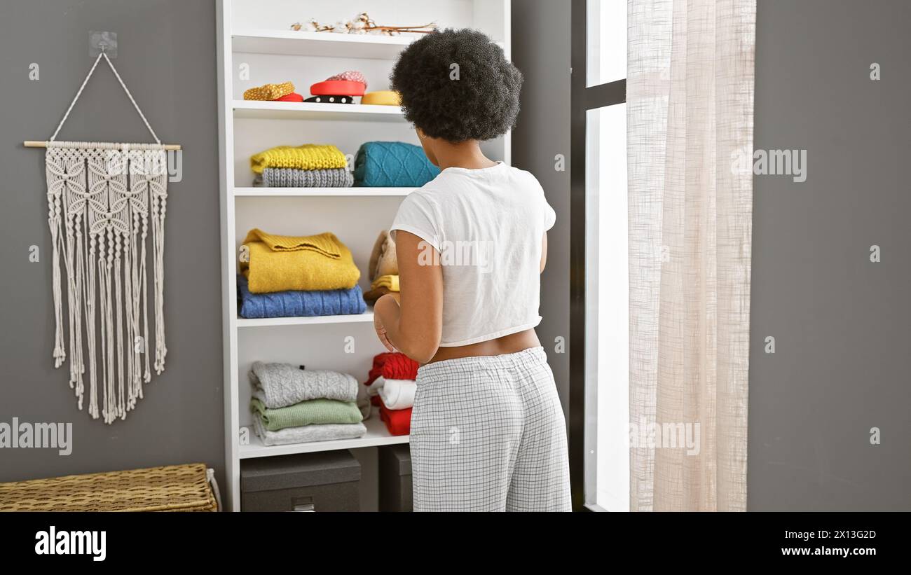 Back view of an african american woman organizing wardrobe at home ...