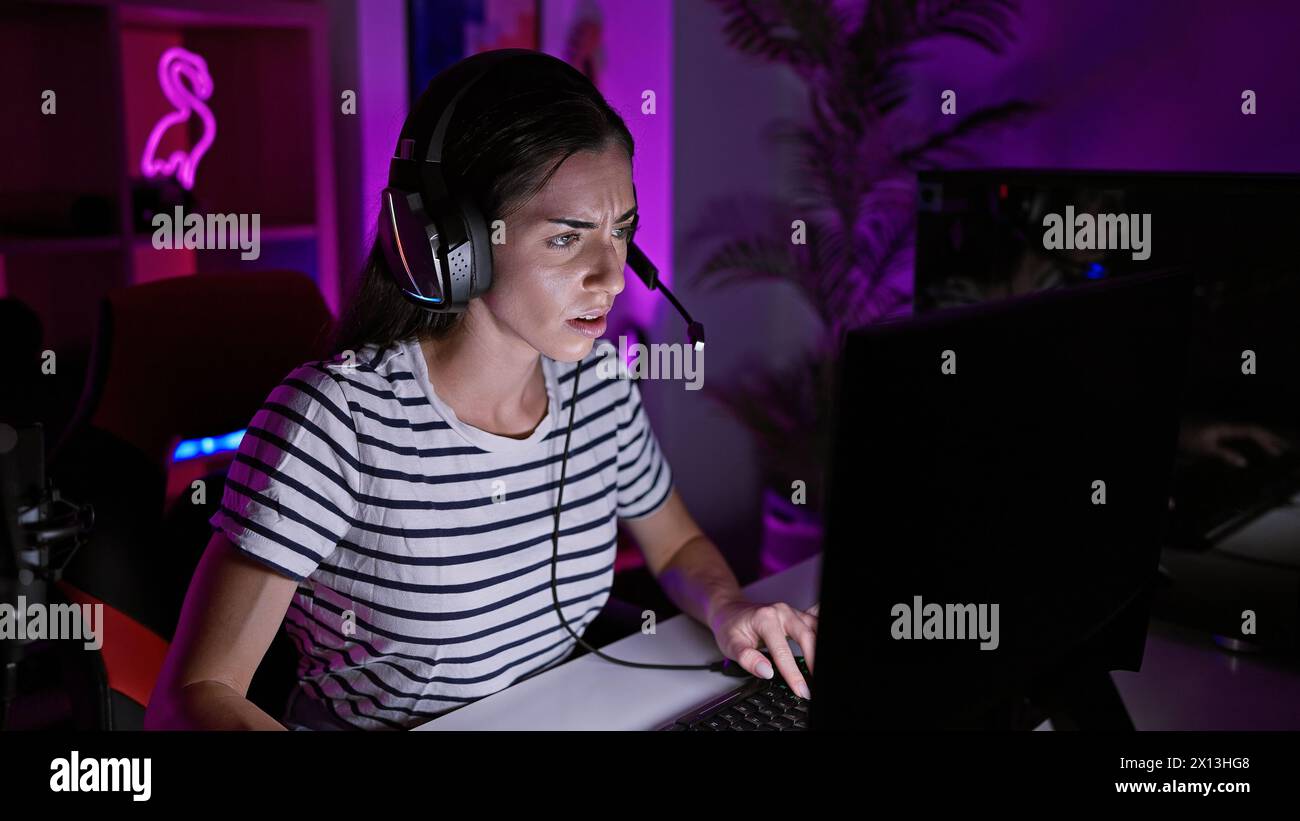 Young beautiful hispanic woman streamer wearing headset playing video ...