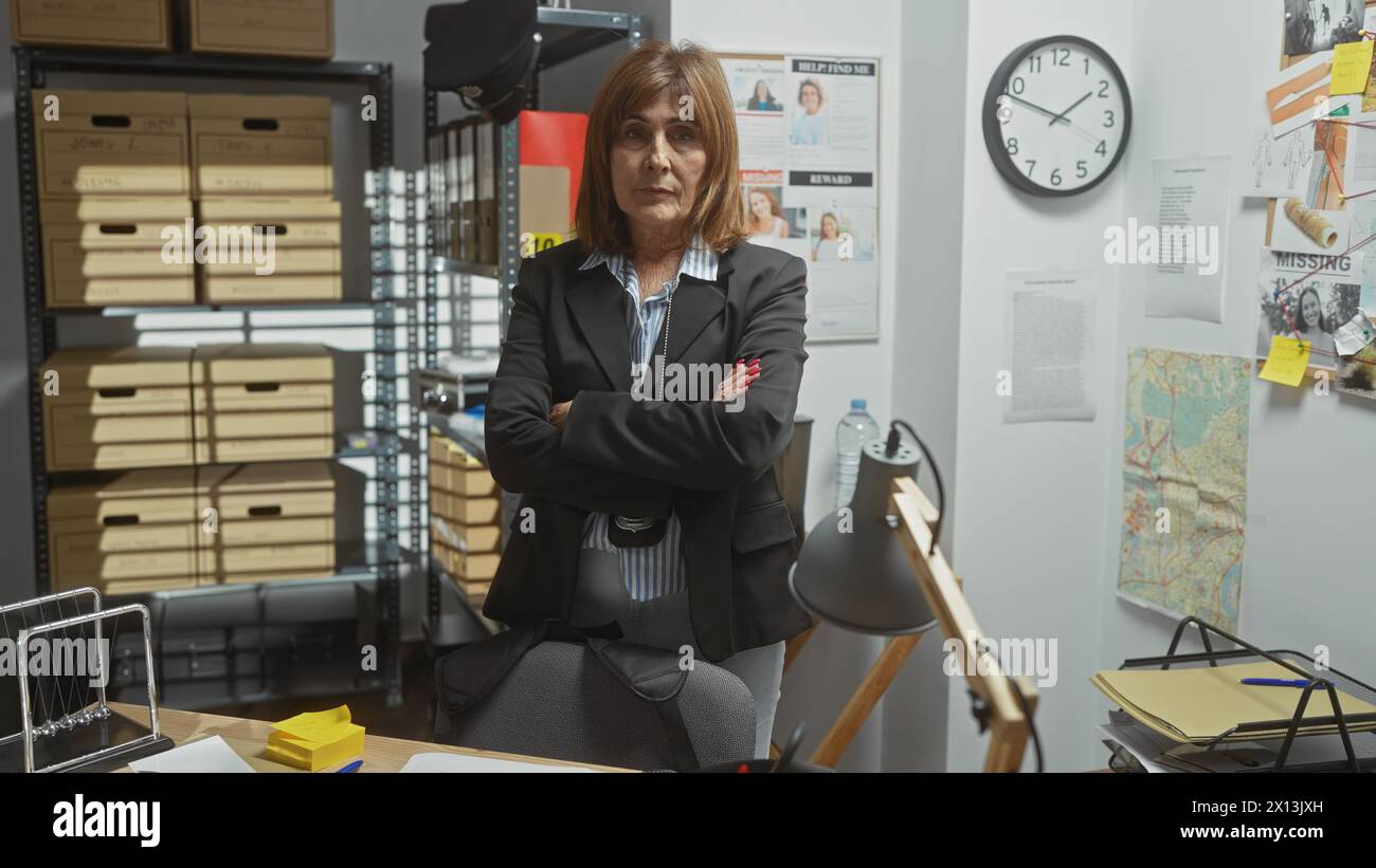 Confident middle-aged woman detective standing arms folded in office ...