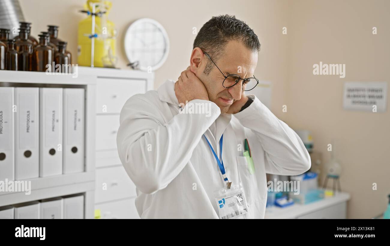 Tired hispanic man in white lab coat inside a laboratory showing stress ...