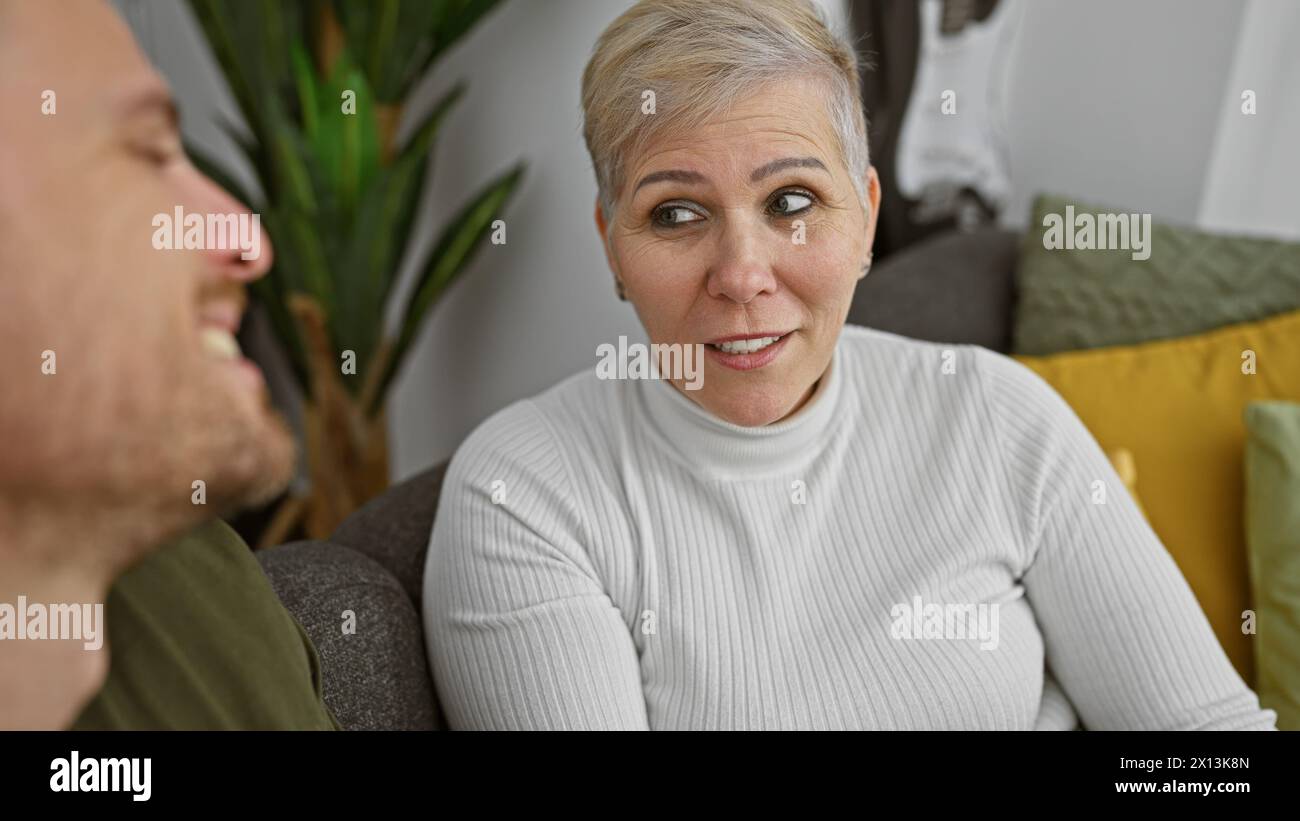 A woman and a man share a light-hearted moment while seated together ...