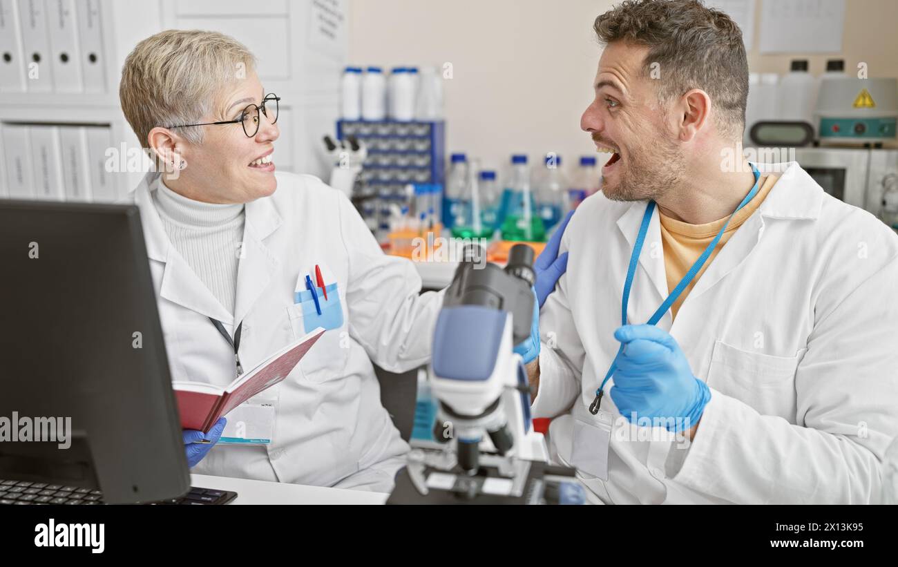 A man and woman, both smiling scientists, revel in teamwork at a ...