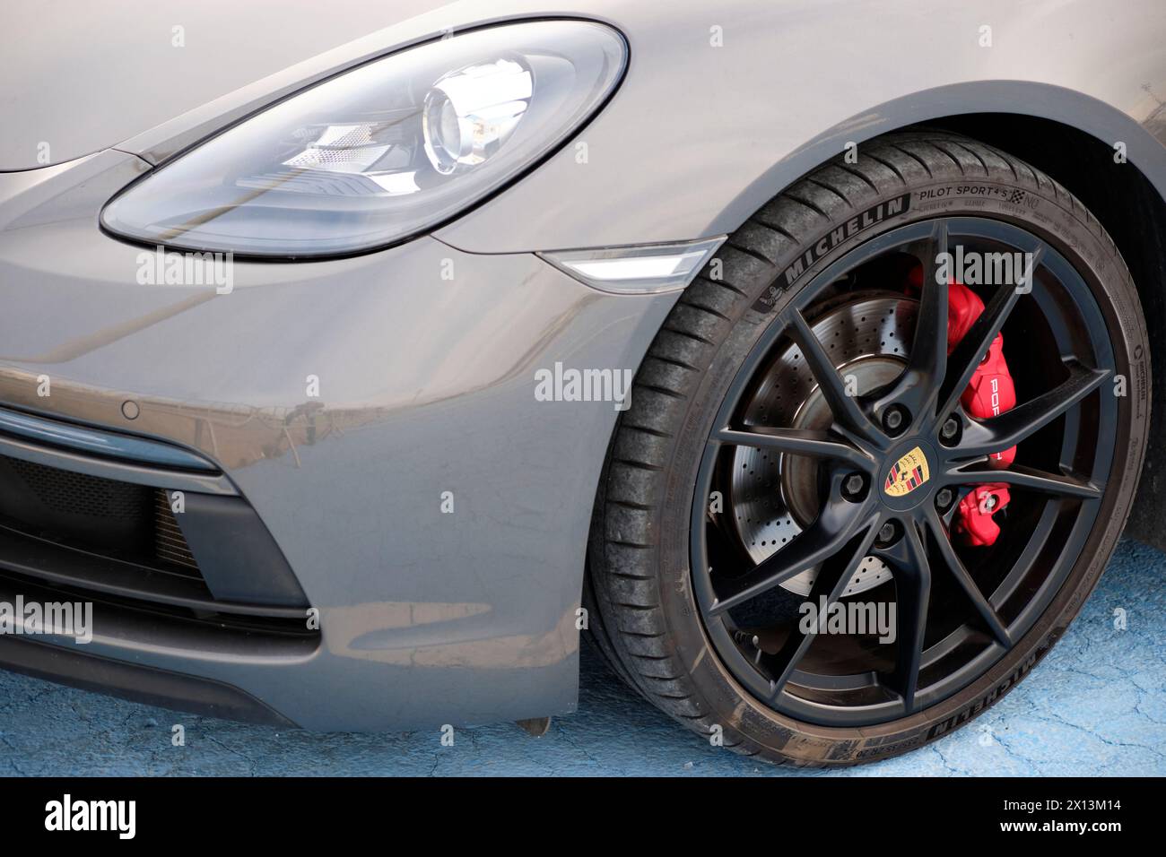 Detail of a satin black wheel with red caliper and the headlight of a ...